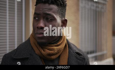 Concerned black man standing outside in city, close-up face portrait ...