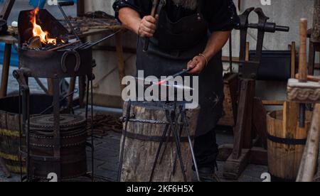 The partial view of a blacksmith hammering the metal in his smithy ...