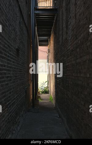 A typical common back alley between two urban buildingsin a black and ...
