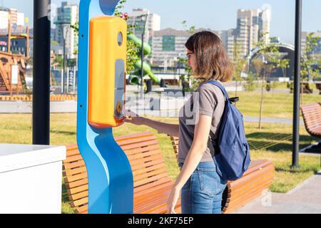 A student girl with a backpack presses the emergency terminal help ...