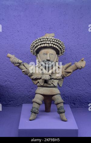 A ceramic figure of a priest in ceremonial dress, wearing a badger mask ...