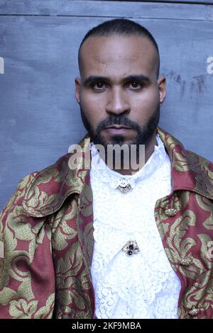 Ethnic man wearing baroque style outfit holding large skull Stock Photo ...