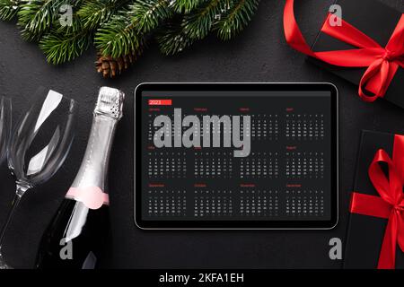 Tablet with calendar, champagne and Christmas decor. Xmas device screen ...