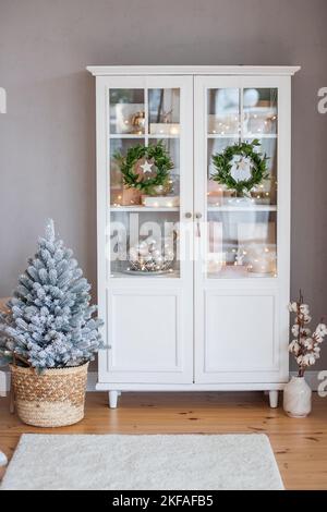 Scandinavian interior style, green wreaths hang on a white sideboard ...