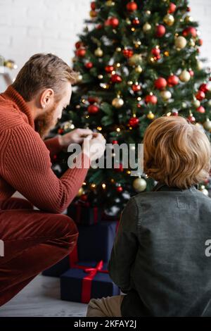 redhead kid with bearded father decorating Christmas tree in living ...