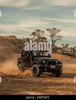 A vertical shot of a black Jeep Wrangler off-roading in the rocky hills ...