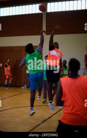 A vertical shot of young people play basketball in gym in Kleve ...