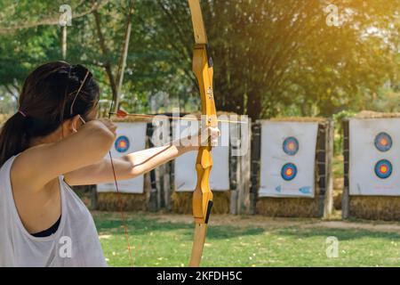 Hands of woman aims archery bow and arrow to colorful target in ...