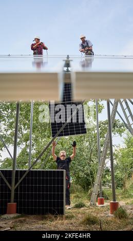 Photovoltaic technicians mounting solar panel on sustainable house with ...