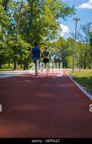Two adult fitness models running in the park Stock Photo - Alamy