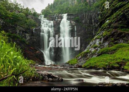 A long exposure shot of a Skjervefossen waterfall in a valley emerging ...