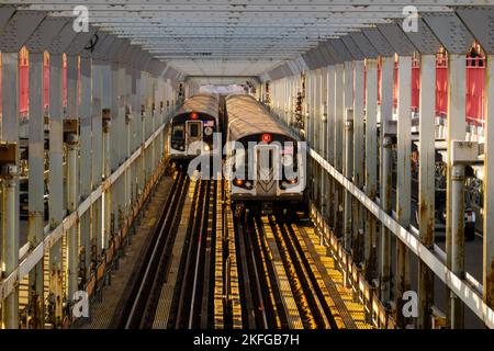two subway trains passing each other on the M line on the Williamsburg bridge in Brooklyn NYC ...