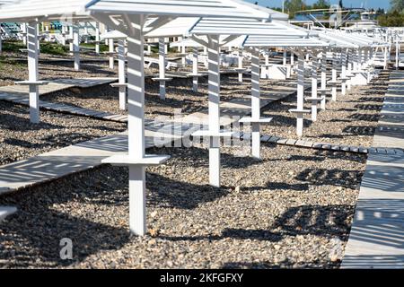 Rows of wooden umbrellas from the sun on the seashore in the morning ...