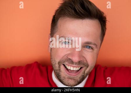 Yyoung man smiling while standing isolated on orange background Stock ...