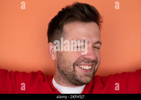 Yyoung man smiling while standing isolated on orange background Stock ...