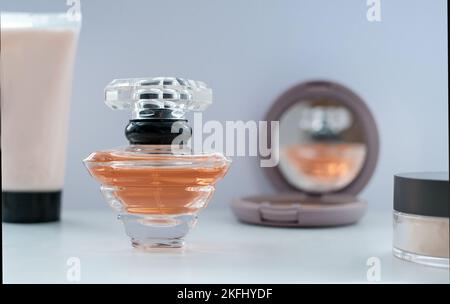 A perfume bottle surrounded by beauty products, powder, lotion Stock ...