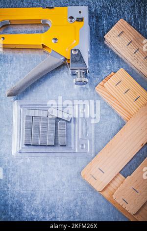 Composition of construction stapler staples on wood board top view ...