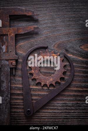 Set of rusty measuring calipers with cog- wheel on vintage dark wooden ...