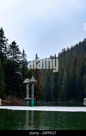Alpine lake Synevyr, wooden statues near the lake, a tourist place in ...