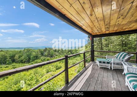 A cabin balcony view of greenery with blue sky and small white clouds ...
