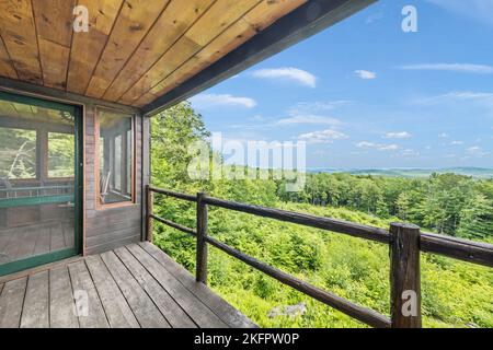 A cabin balcony view of greenery with blue sky and small white clouds ...