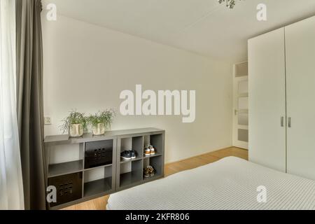 Comfortable bed with blanket placed near wardrobe in light bedroom ...
