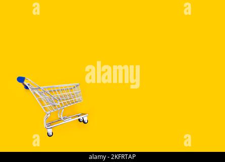 empty shopping cart over yellow background, mini metal cart isolated on ...