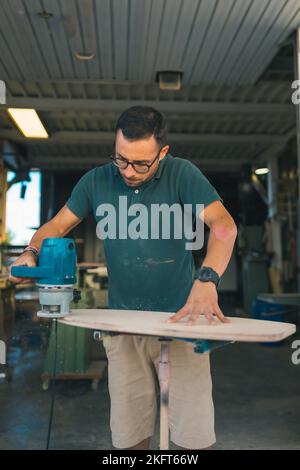 Focused male carpenter in casual clothes cutting wood with milling ...