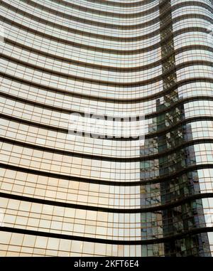 From below curvy modern high glass rise building with spire on city ...