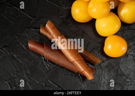 Pastila fruit skin rolls with fruits on a black background. Vegetarian ...