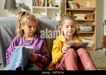 Lttle girl playing online on tablet pc sitting on floor together with ...