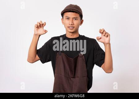 Portrait of annoyed Asian barista man in brown apron making angry hand ...