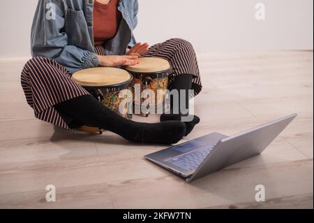 A faceless woman sits on the floor at home and watches educational ...