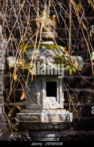 A close up of a traditional toro stone lantern within a Japanese garden ...
