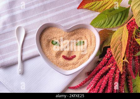 Amaranth grits in a faience white plate in the form of heart with ...