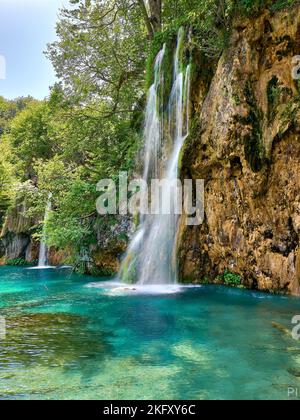 A vertical shot of a waterfall coming out of a huge cliff Stock Photo ...
