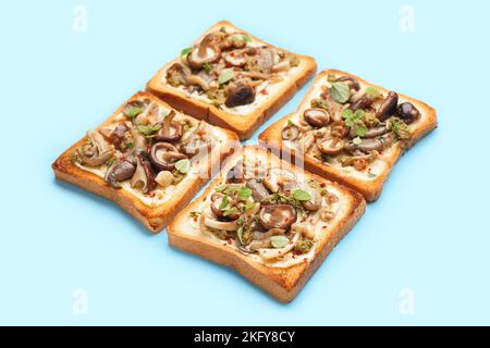 Delicious toasts with cream cheese, mushrooms and pesto sauce on color ...