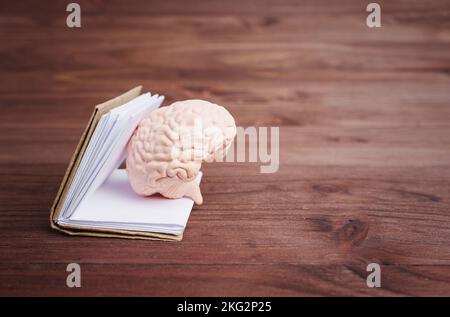 Human brain figurine placed on a wooden table with toy laptop ...
