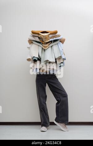 Woman holding pile of clothes. Minimal fashion faceless portrait Stock ...