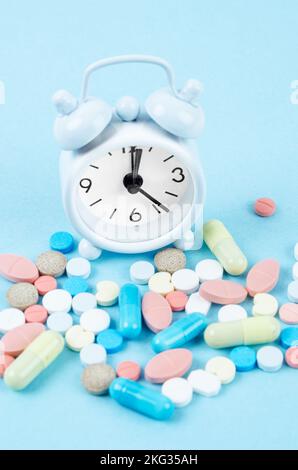 White alarm clock and many drug on a yellow background. Taking medicine ...