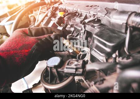 A auto mechanic is installing automobile iridium spark plugs into the ...