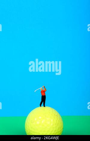 Conceptual image of a miniature figure golfer teeing off from a golf ...