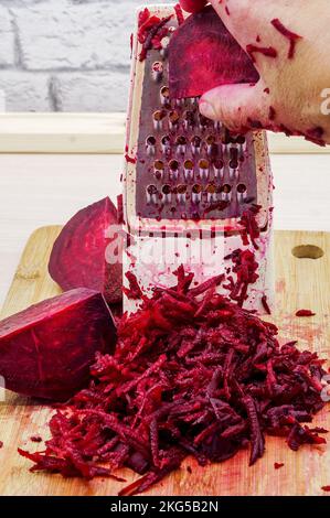 Grate beets on a grater. Grated beets. Grate the beetroot on the grater ...