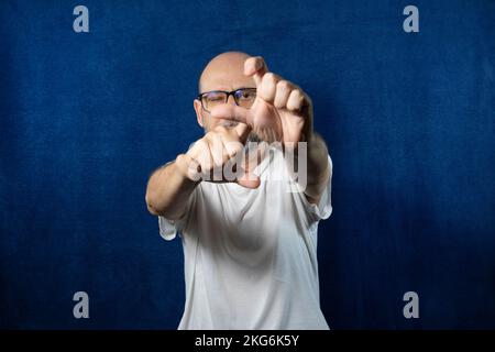 The portrait of a bearded bald man imitating something with his hands ...