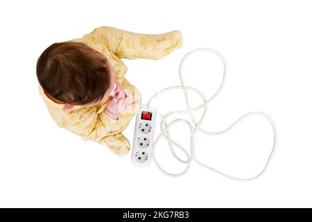 Toddler baby boy plays with electric wires while sitting on the floor ...
