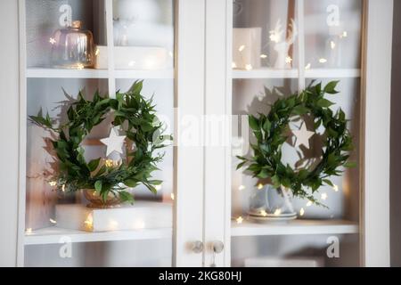 Scandinavian interior style, green wreaths hang on a white sideboard ...