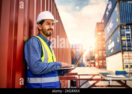 Handsome Engineer or foreman wears PPE checking container storage with ...