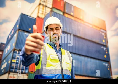 Handsome Engineer or foreman wears PPE checking container storage with ...