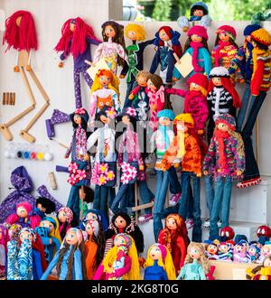 A display of toy rag dolls made from wood and bright colorful cloth ...