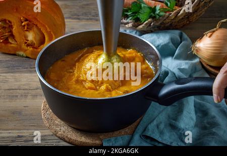 process of mixing stewed vegetables. pumpkin cream soup in a pot on ...